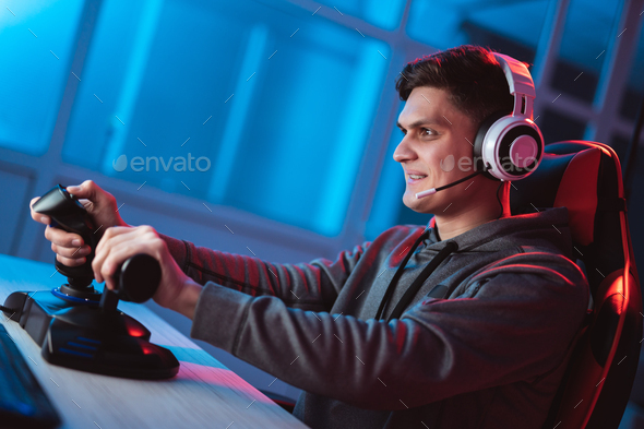 The gamer sitting at the table and playing video games in the neon room ...