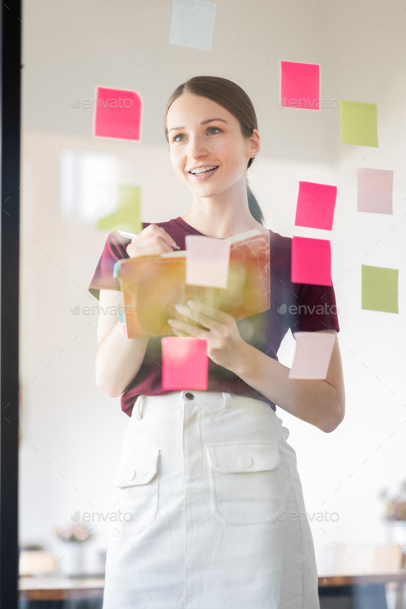 Business woman meeting at office and use post it notes in glass wall to ...