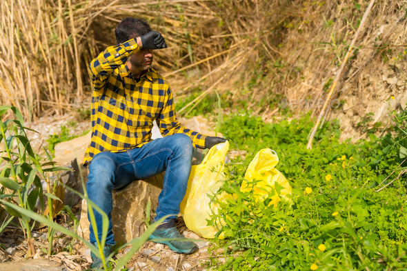 Tired man picking up trash in a forest. Ecology, clean nature from ...