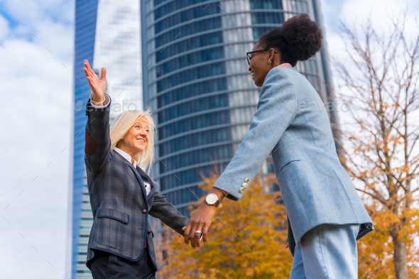 Middle-aged multi-ethnic businesswomen and executives, hugging outside ...