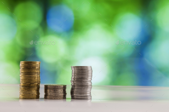 Growing coins stacks with green and blue sparkling bokeh background. Stock Photo by bilanol
