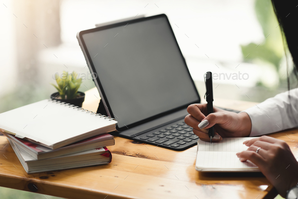 Close up of young woman hand taking notes, documents and tablet placed ...