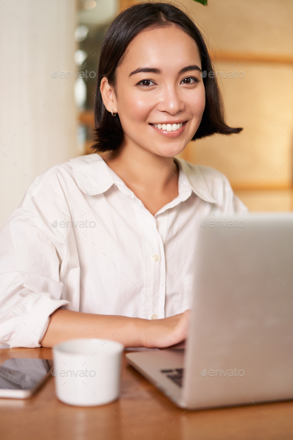 Stylish brunette woman with laptop, sitting in cafe and drinking coffee ...