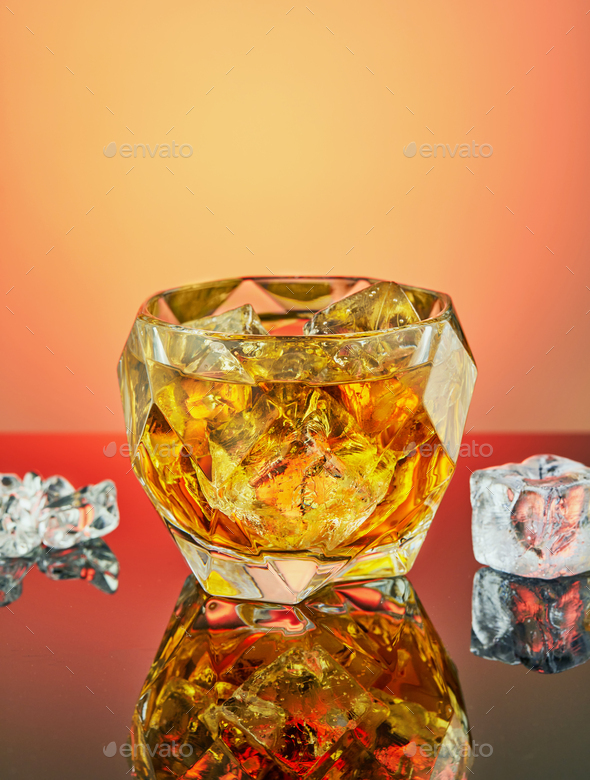 Crystal goblet with luxury whiskey and ice cubes side view on gradient ...