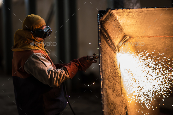 Demolition construction worker using a flame torch to cut up heavy ...