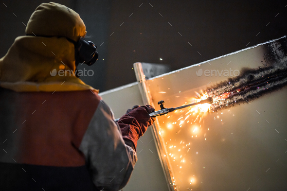 Demolition construction worker using a flame torch to cut up heavy ...