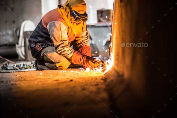 Demolition construction worker using a flame torch to cut up heavy ...