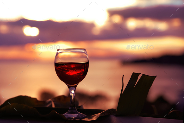 Red wine in a glass on the blurred background of the sky, clouds and ...