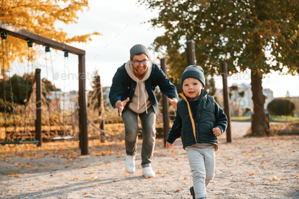 Running, having fun. Father and young son is together outdoors at ...