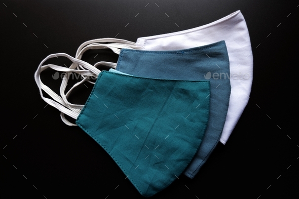 Overhead shot of three different colored face masks on a black surface ...