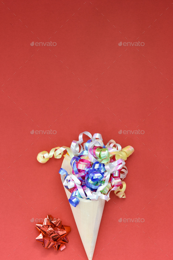 Paper cone with colorful party streamers on red background. Stock Photo ...