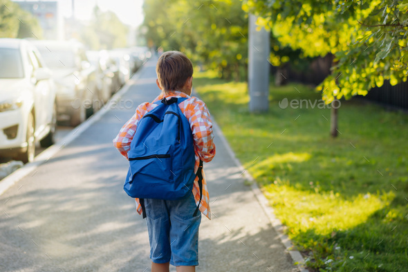 caucasian boy walking to school wearing school bag. Begining of ...
