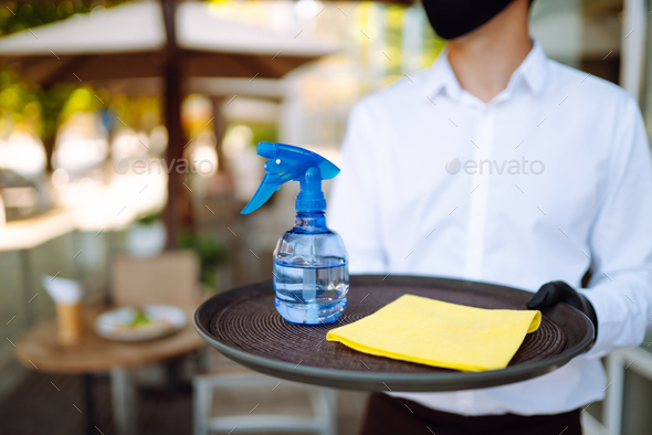 Disinfecting to prevent COVID-19. Waiter cleaning the table with ...