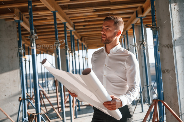 Standing and reading plan. Man is working on the construction site at ...