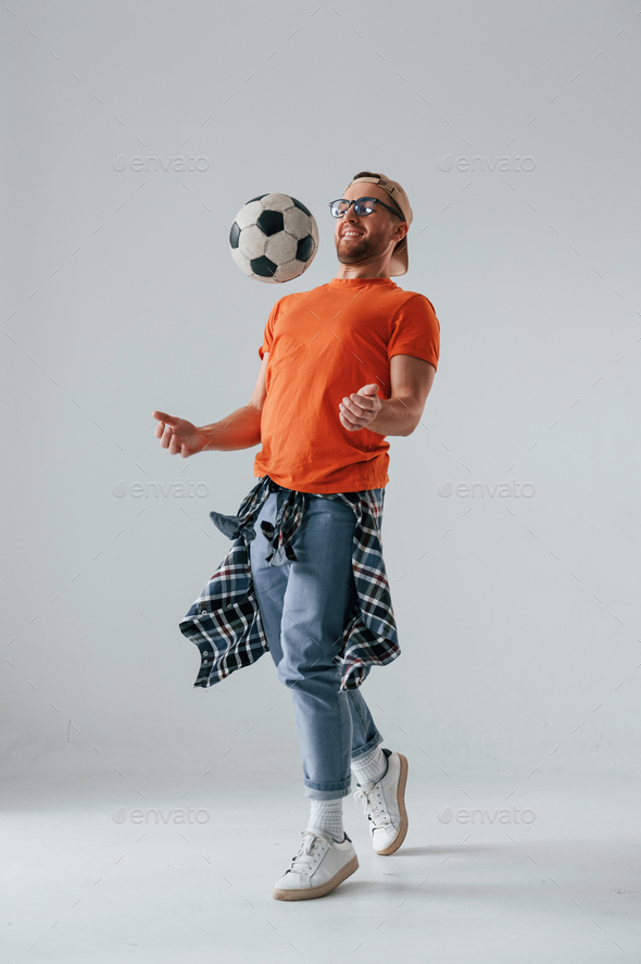 Active football fan is with soccer ball. Handsome man is in the studio ...