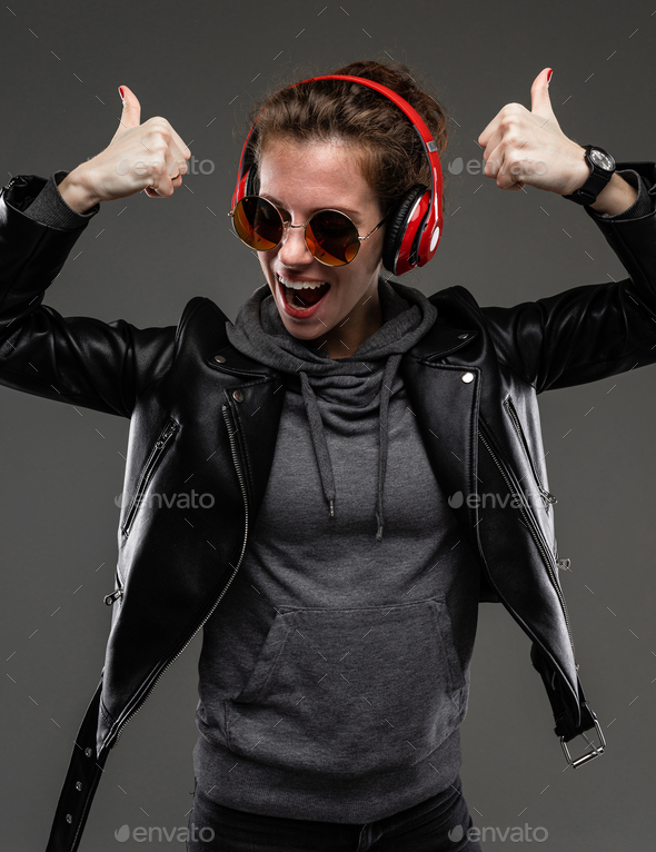 Caucasian girl with rough facial features in a black jacket listen to ...