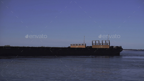 Cargo ship sailing on river on clear day. Clip. Merchant ship or barge ...