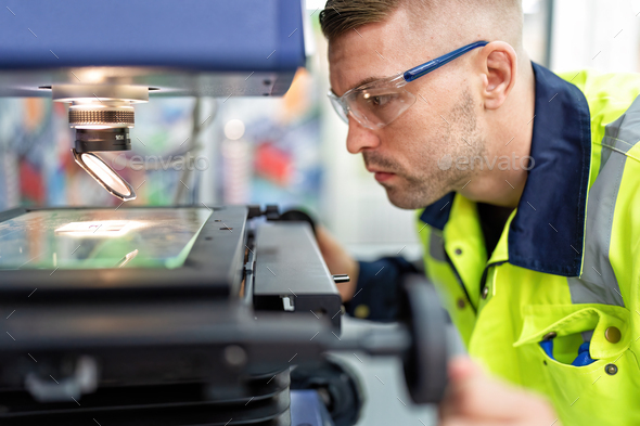 Engineer sitting in robot fabrication room use measuring microscope ...