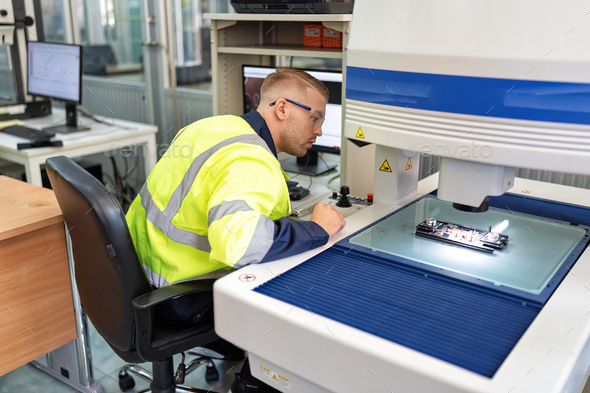 Engineer sitting in robot fabrication room use measuring microscope ...