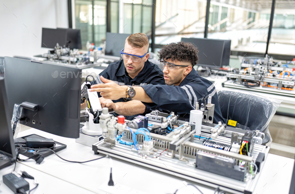 Engineer sitting in robot fabrication room quality checking electronic ...
