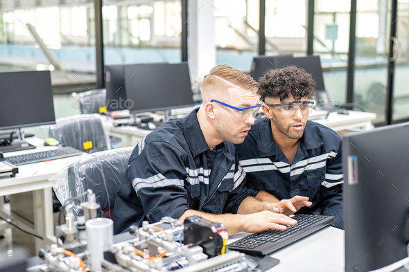 Engineer sitting in robot fabrication room quality checking electronic ...