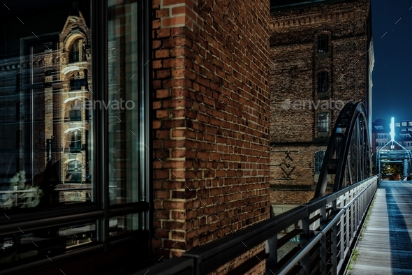 Horizontal shot of brick buildings in a nighttime city with a bridge ...