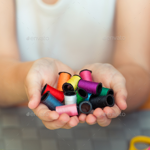 happy cute little girl shows spools of thread Stock Photo by tan4ikk