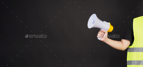Hand is hold megaphone and wear Safety Vest on black background. Stock ...