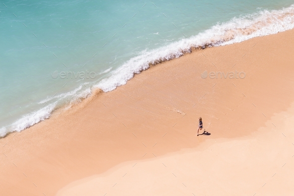 Sandy beach with foamed waves and a single person Stock Photo by wirestock
