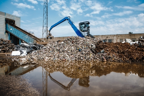 Claw crane grabbing the scrap at a rubbish dump Stock Photo by wirestock