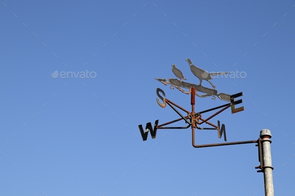 Wind vane isolated on a blue sky background. Wind direction and weather ...
