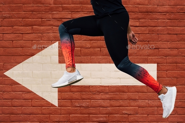 Young man running and working out with a brick wall and an arrow on the ...