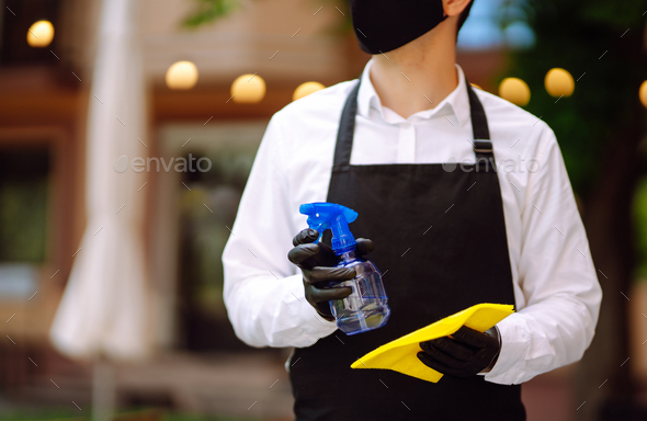 Disinfecting to prevent COVID-19. Waiter cleaning the table with ...