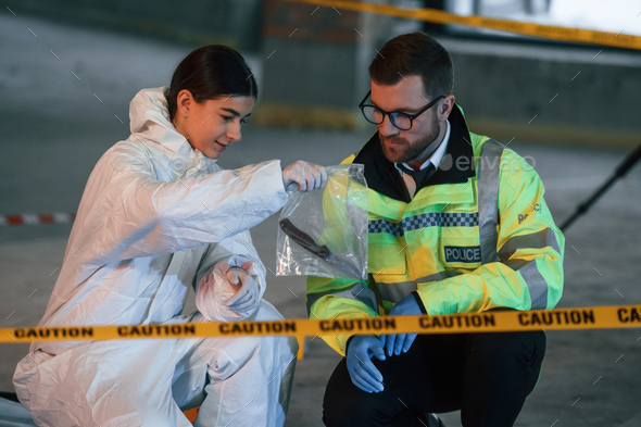 Holding knife in package. Two detectives are collecting evidence in a ...