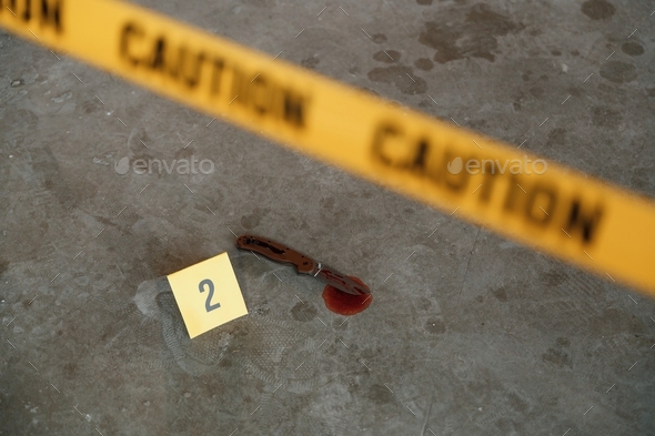 Crime scene. Top view of knife clue with blood. Police causion tape ...