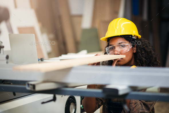 Young black female carpenter wearing safety goggles and hard hat for ...