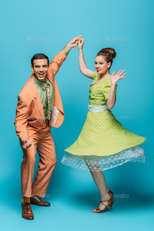stylish dancers holding hands while dancing boogie-woogie on blue ...