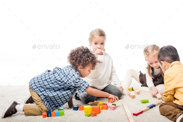 multicultural kids playing with wooden blocks on carpet, isolated on ...