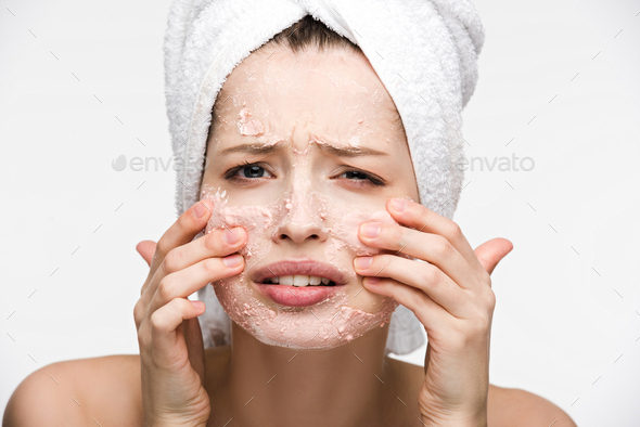 displeased girl with facial peeling mask touching face isolated on ...