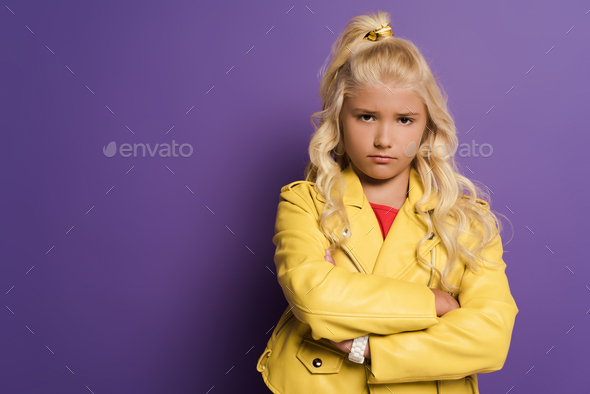 offended kid with crossed arms looking at camera on purple background ...