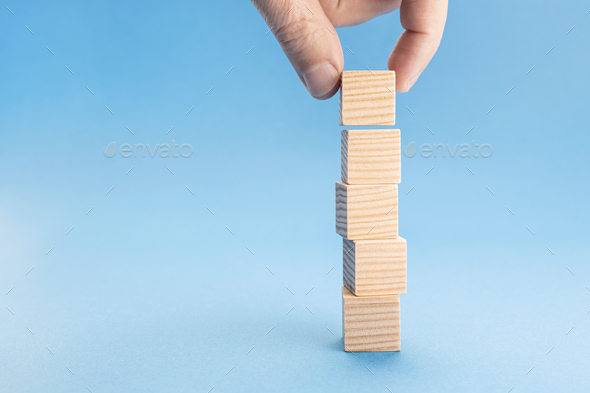 Hand putting a fifth wooden cube on top of other stacked cubes Stock ...