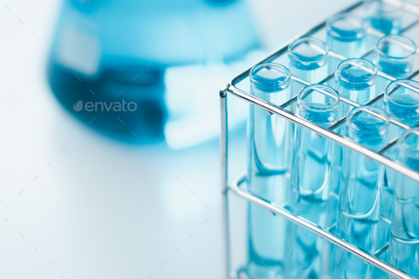 Test tubes and erlenmeyer flask filled with blue sample chemicals in ...