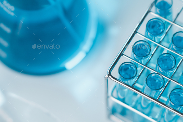 Test tubes and erlenmeyer flask filled with blue sample chemicals in ...