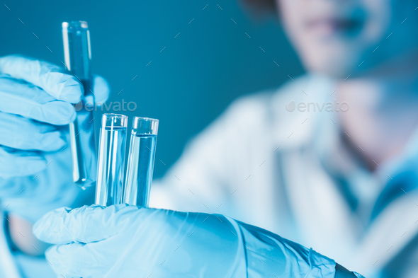 Scientist hand hold test tubes filled with blue sample chemicals in ...