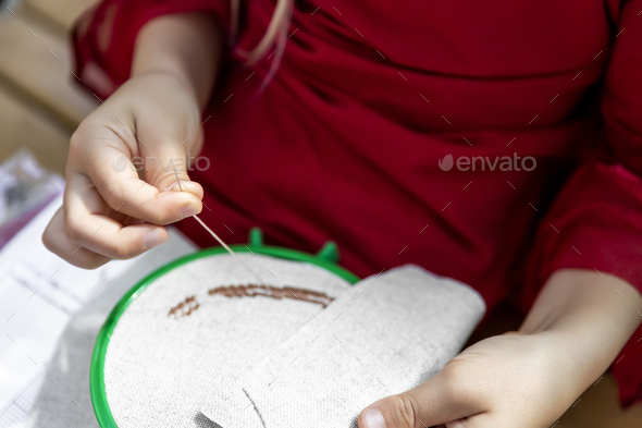 Close-up detail female child hands embroidering round hoop fabric frame ...