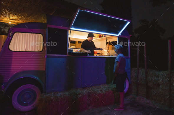 Cook serving a customer in his food truck Stock Photo by inesperadacobos