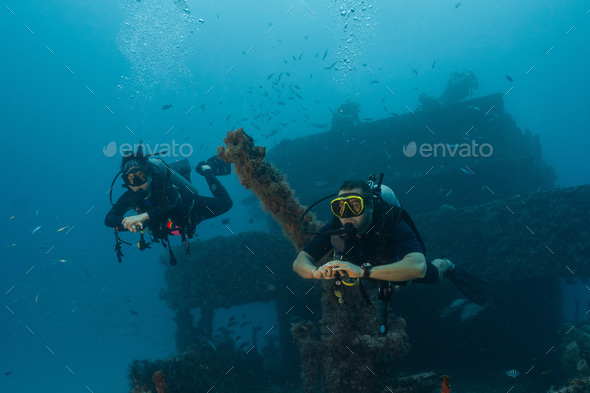 couple of divers posing in front of a sunken ship, technical diving ...