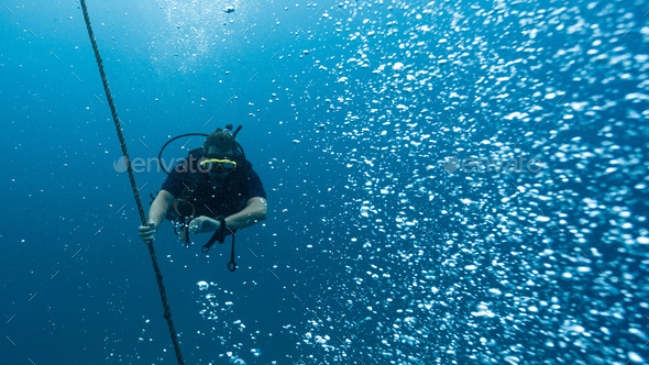 professional diver checking his dive computer to ascend safely. holding ...