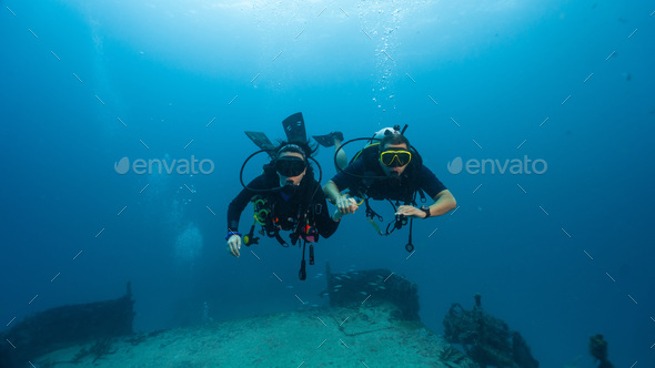 couple of divers posing in front of a sunken ship, technical diving ...