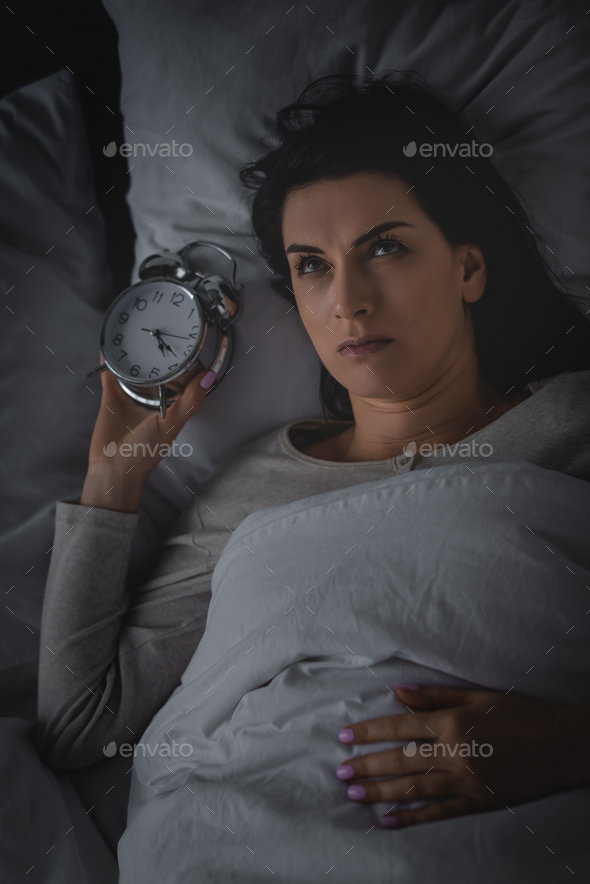 top view of awake woman lying on bed with alarm clock Stock Photo by ...